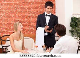 Young waiter approaching an older couple to take their order in a ...