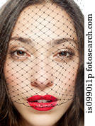 Woman covering part of face with neck of sweater, looking at camera ...