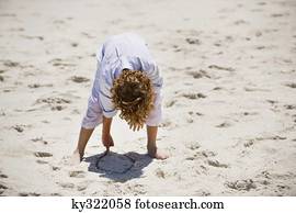 Little boy on beach, bending toward sand, full length, side view Stock ...