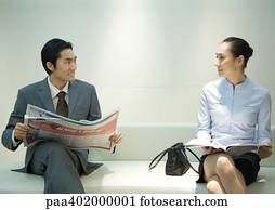 Two people sitting across from each other at table, looking at document ...