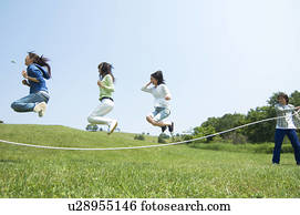 Four young people skipping in field Stock Photo | u12568487 | Fotosearch